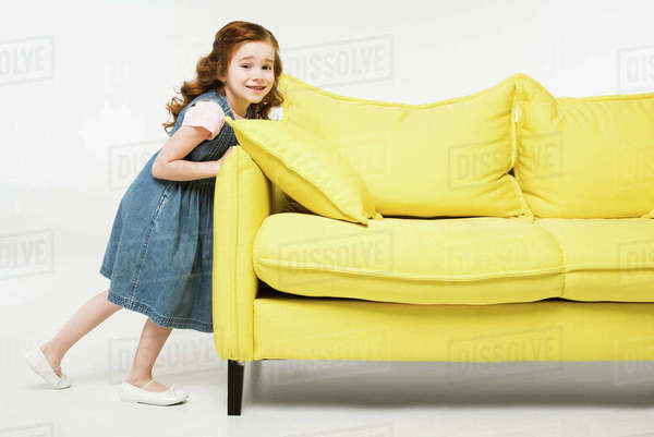 Stylish little kid in dress pushing sofa isolated on white - Royalty ...