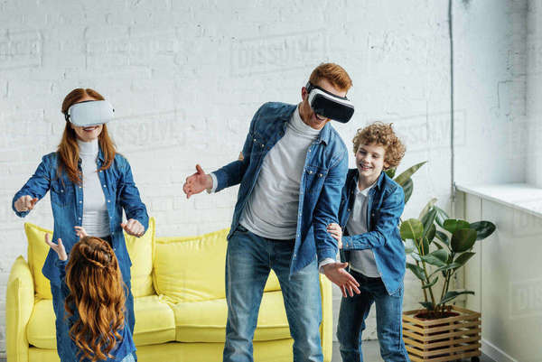 Parents using vr glasses having fun together with their children ...