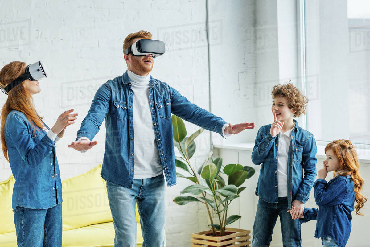 Parents using vr glasses together with their children at home - Royalty ...