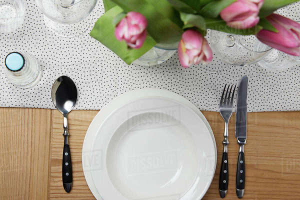 Dinnerware with plates on table with flowers in vase - Stock Photo ...