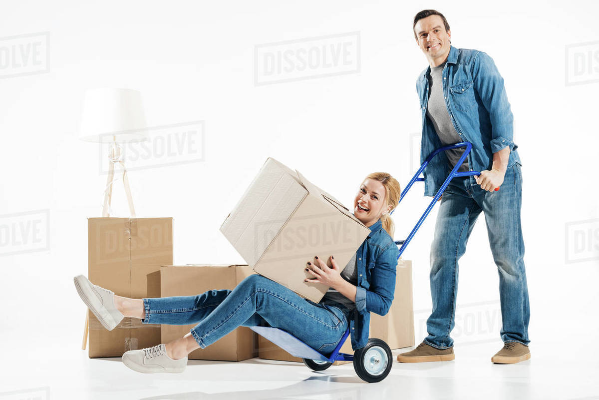 Man pushing trolley cart with woman holding box during flat moving ...