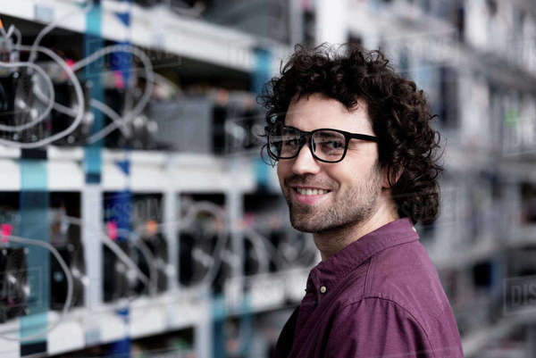 Happy young computer engineer at cryptocurrency mining farm looking at ...