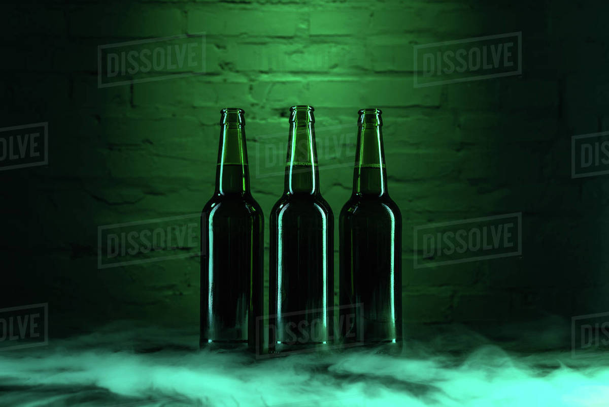Three open green beer bottles and smoke in green light - Royalty-free ...