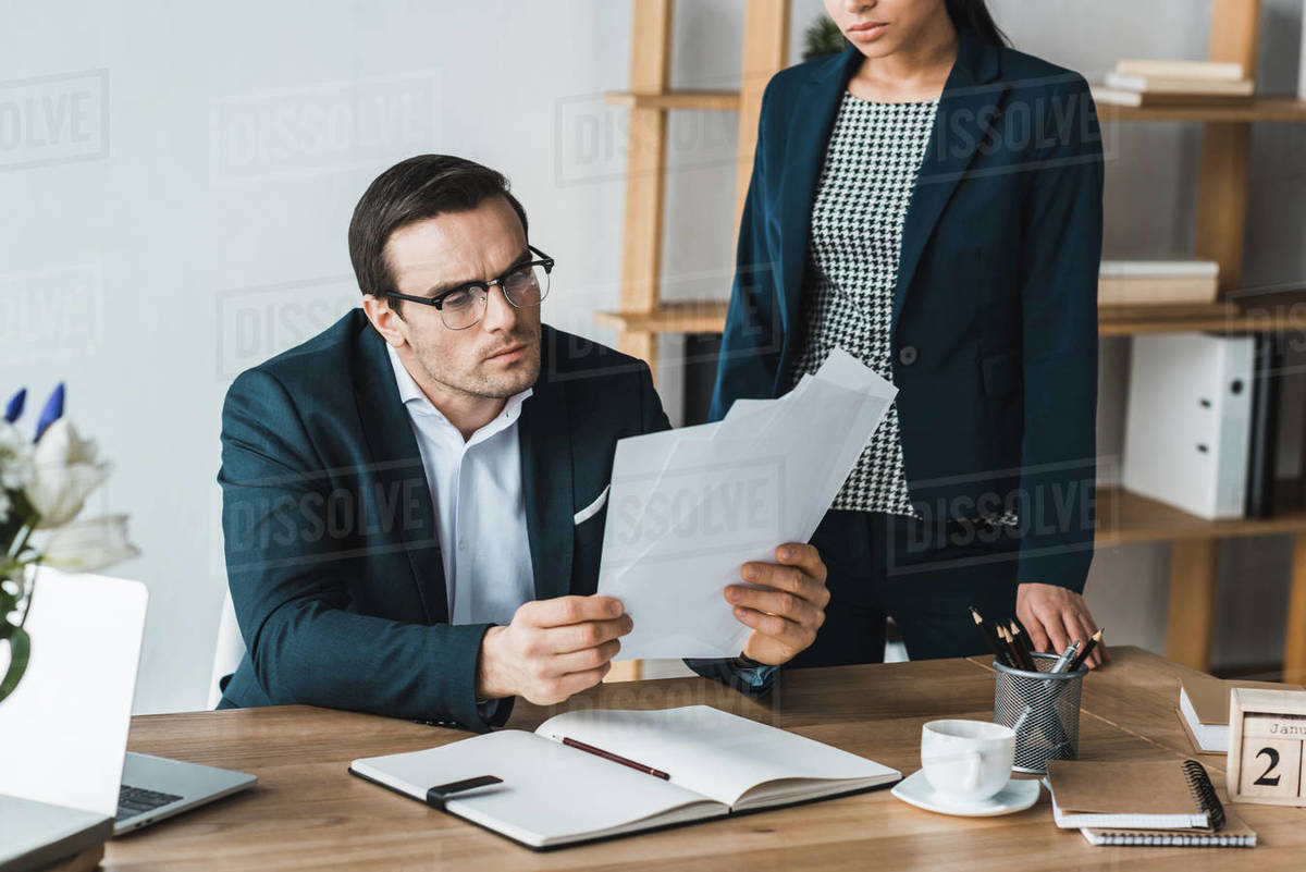 Business colleagues looking at contract papers by table in office ...