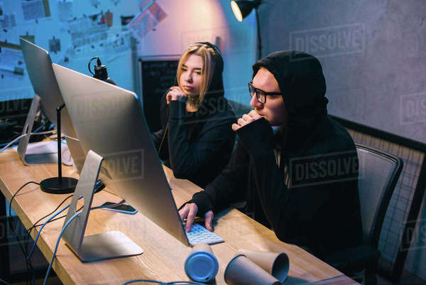Couple of young hackers working together in dark room - Royalty-free ...