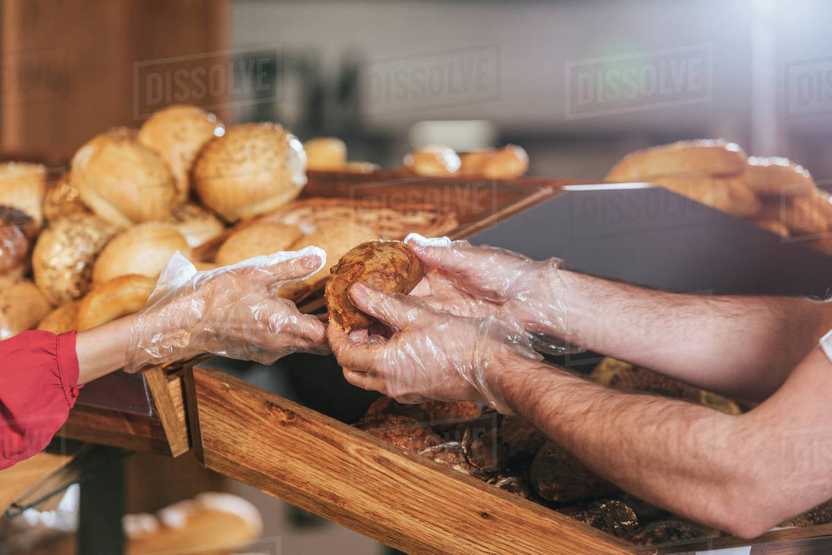 Cropped shot of shop assistant giving loaf of bread to woman in ...