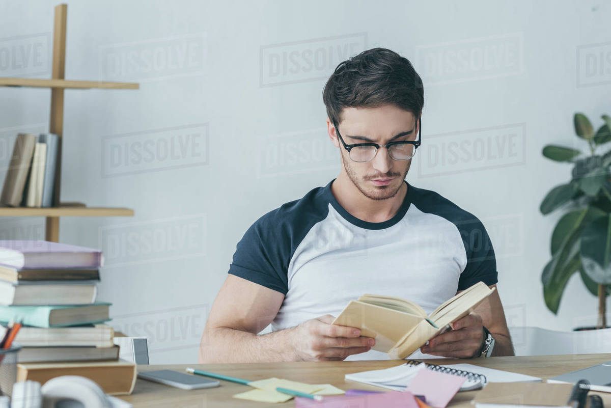 Handsome male student reading book - Royalty-free Stock Photo | Dissolve