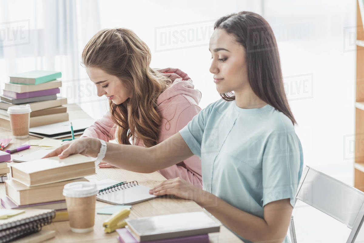 Multiethnic girls studying together with books - Stock Photo - Dissolve