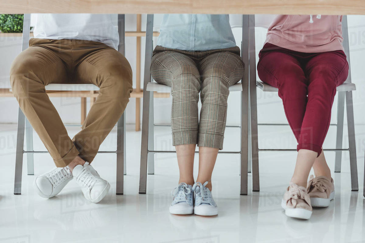 Cropped view of people sitting at table - Stock Photo - Dissolve