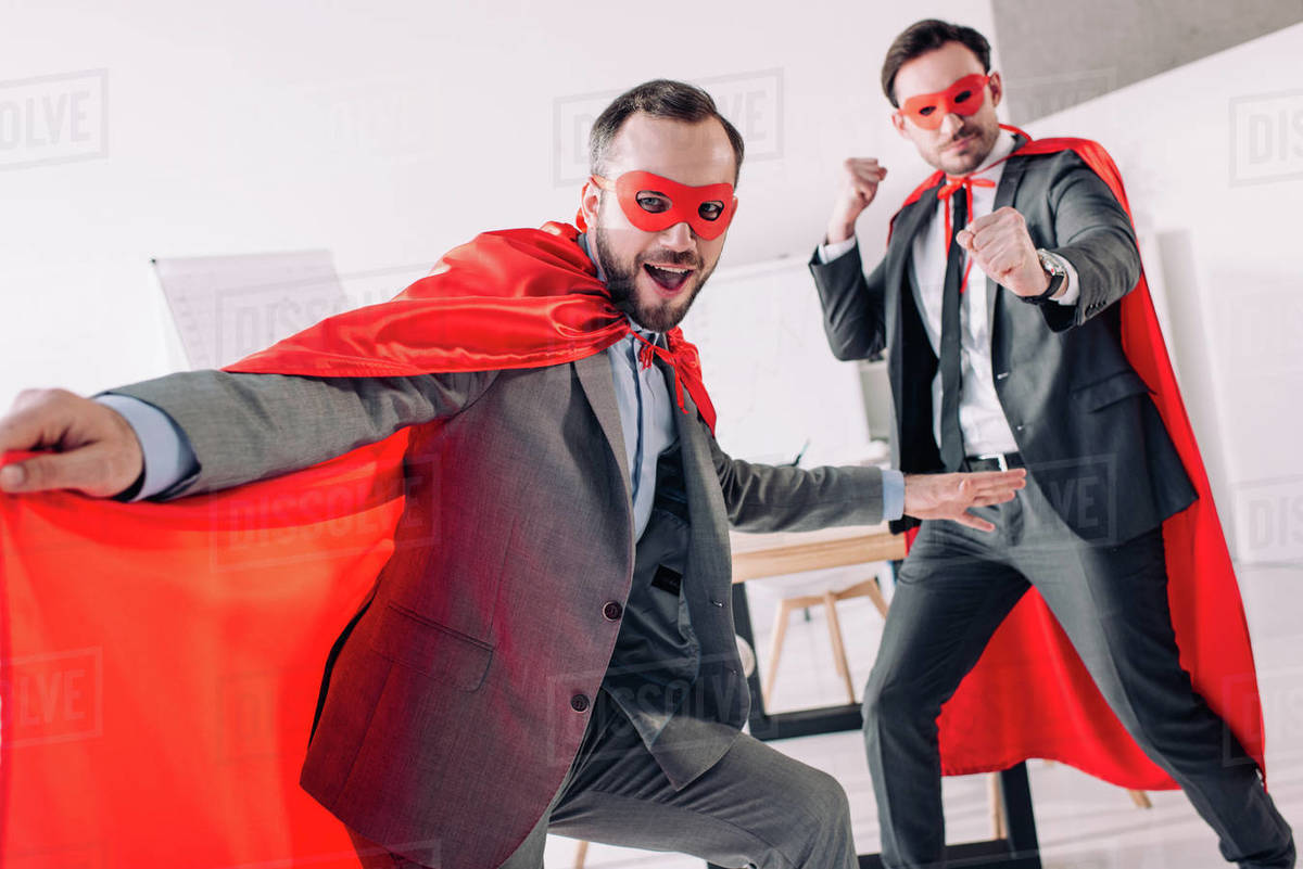 Handsome super businessmen in masks and capes having fun in office ...