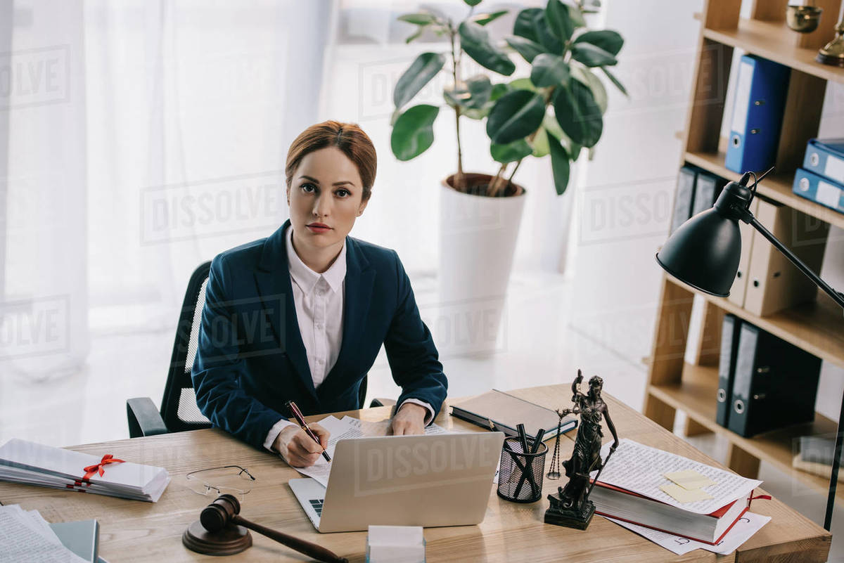 Female lawyer in suit at workplace with laptop, gavel and Femida in ...