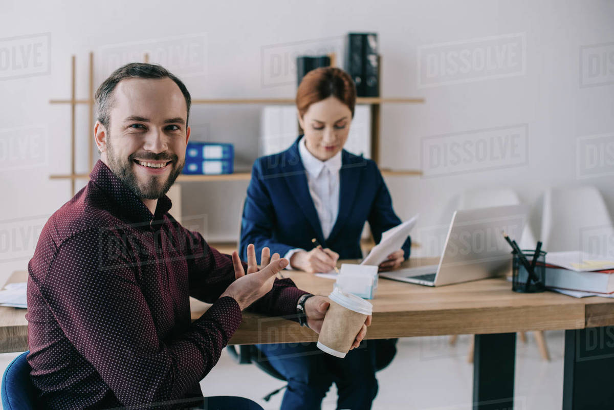 Selective focus of smiling client with coffee to go pointing at ...