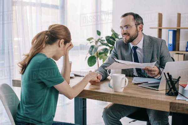 Businessman and client shaking hands during meeting in office - Royalty ...