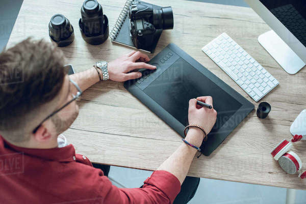 Freelancer man drawing with graphic tablet by table with computer ...