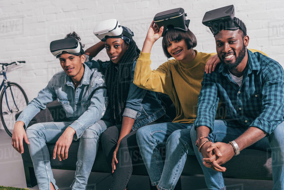 Young multicultural friends with lifted up virtual reality headsets ...
