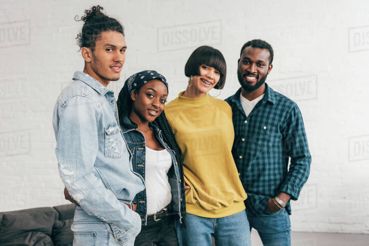 Portrait of smiling group of multicultural friends standing in room ...
