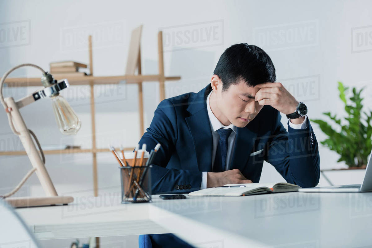 Thoughtful overworked asian businessman at workplace - Royalty-free ...