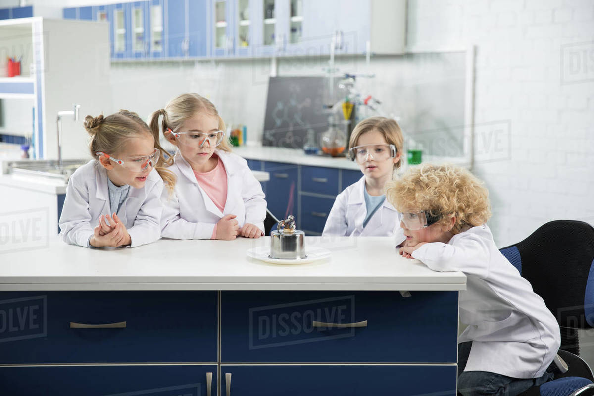 Kids in lab coats and protective glasses making experiment in ...