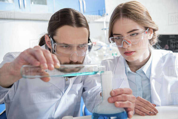 Young male and female scientists making experiment in laboratory ...