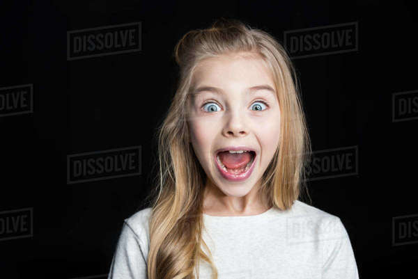 Cute blonde girl screaming and looking at camera isolated on black ...