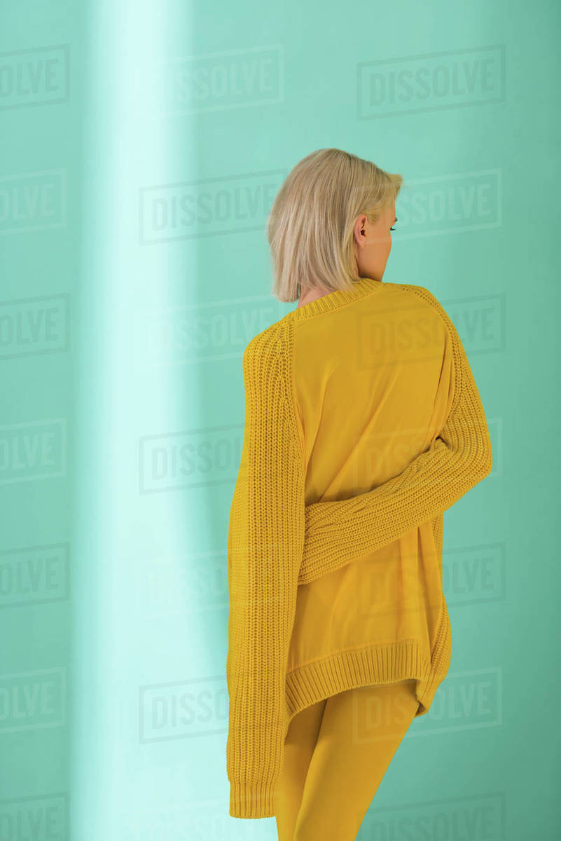 Back view of woman in yellow sweater posing on blue background - Stock ...