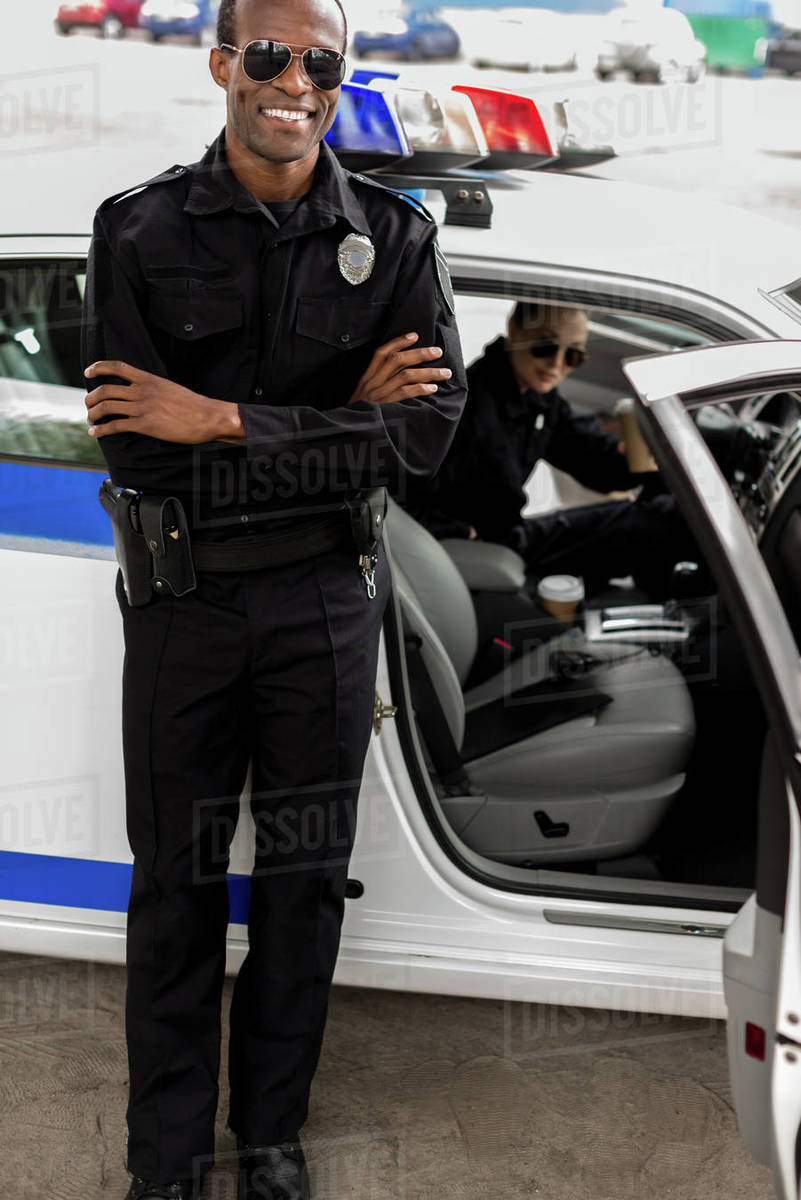 Handsome young policeman with crossed arms standing in front of police ...