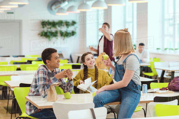 Happy high school students taking lunch together at school cafeteria ...