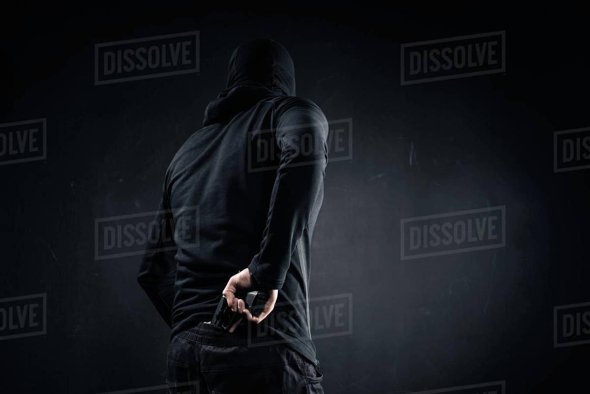 Thief hiding gun behind his back - Royalty-free Stock Photo | Dissolve