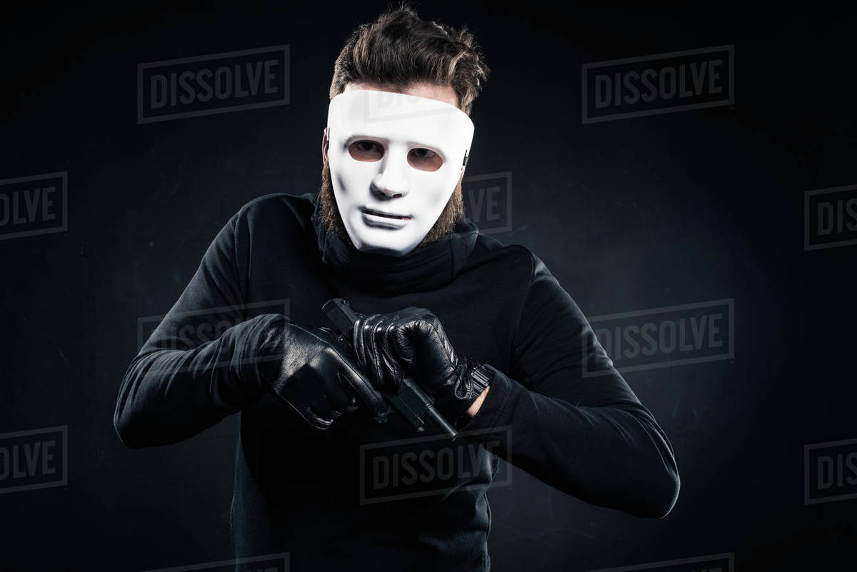 Robber in white mask and black clothes recharging his gun - Stock Photo ...