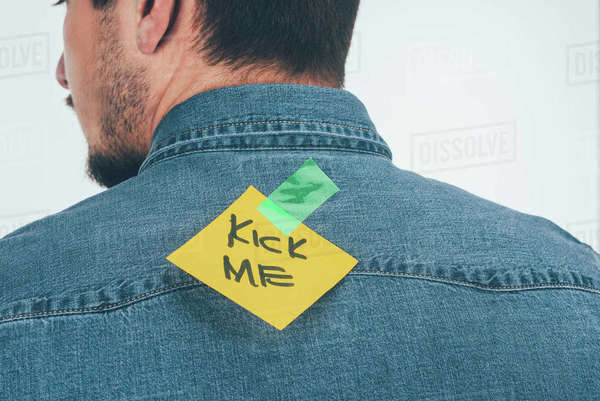Back view of man with note on sticky tape with kick me lettering on ...