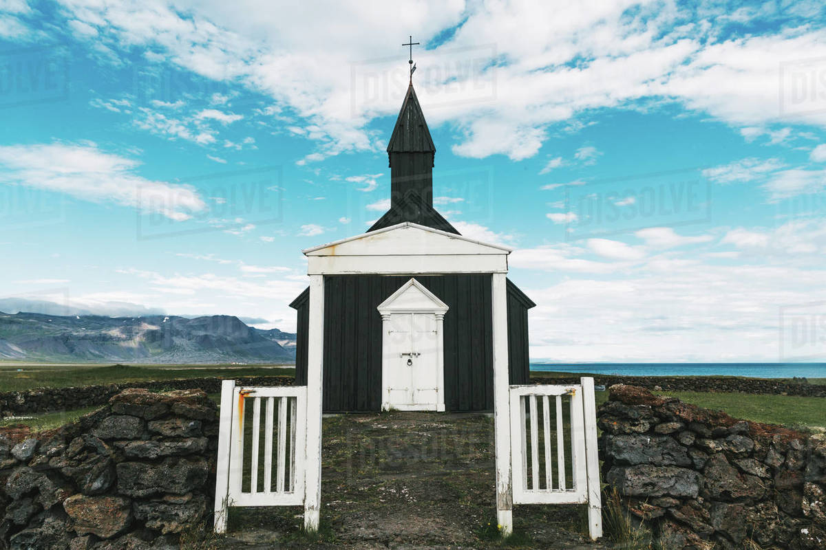 White gates and stone wall at entering to small church in budir ...