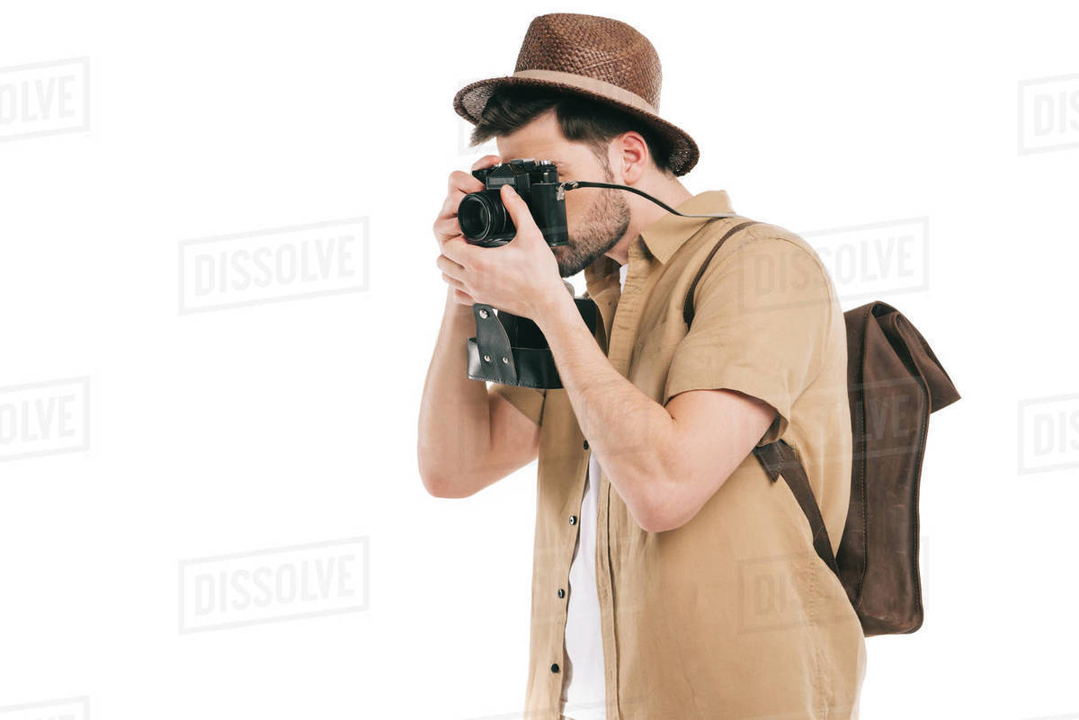 Side view of young man with backpack photographing with camera isolated ...