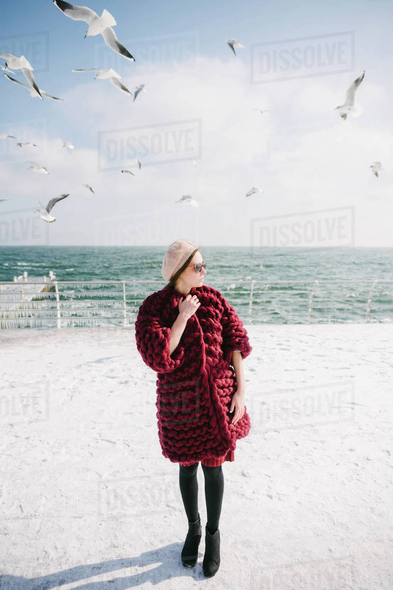 Beautiful girl in trendy merino wool cardigan posing on quay near sea ...