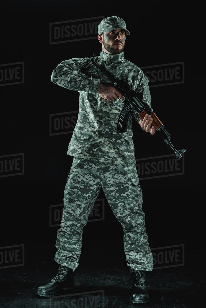 focused soldier in military uniform with rifle isolated on black ...