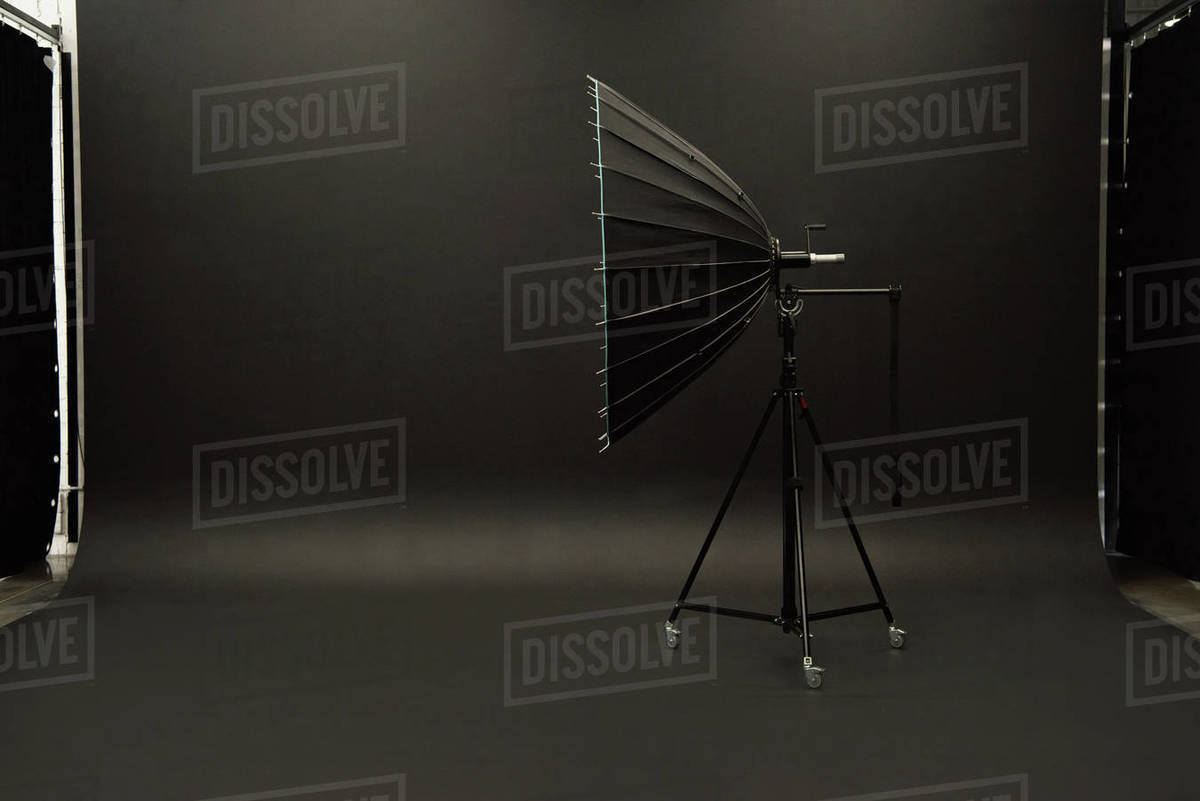 Big studio light standing on black studio backdrop - Stock Photo - Dissolve