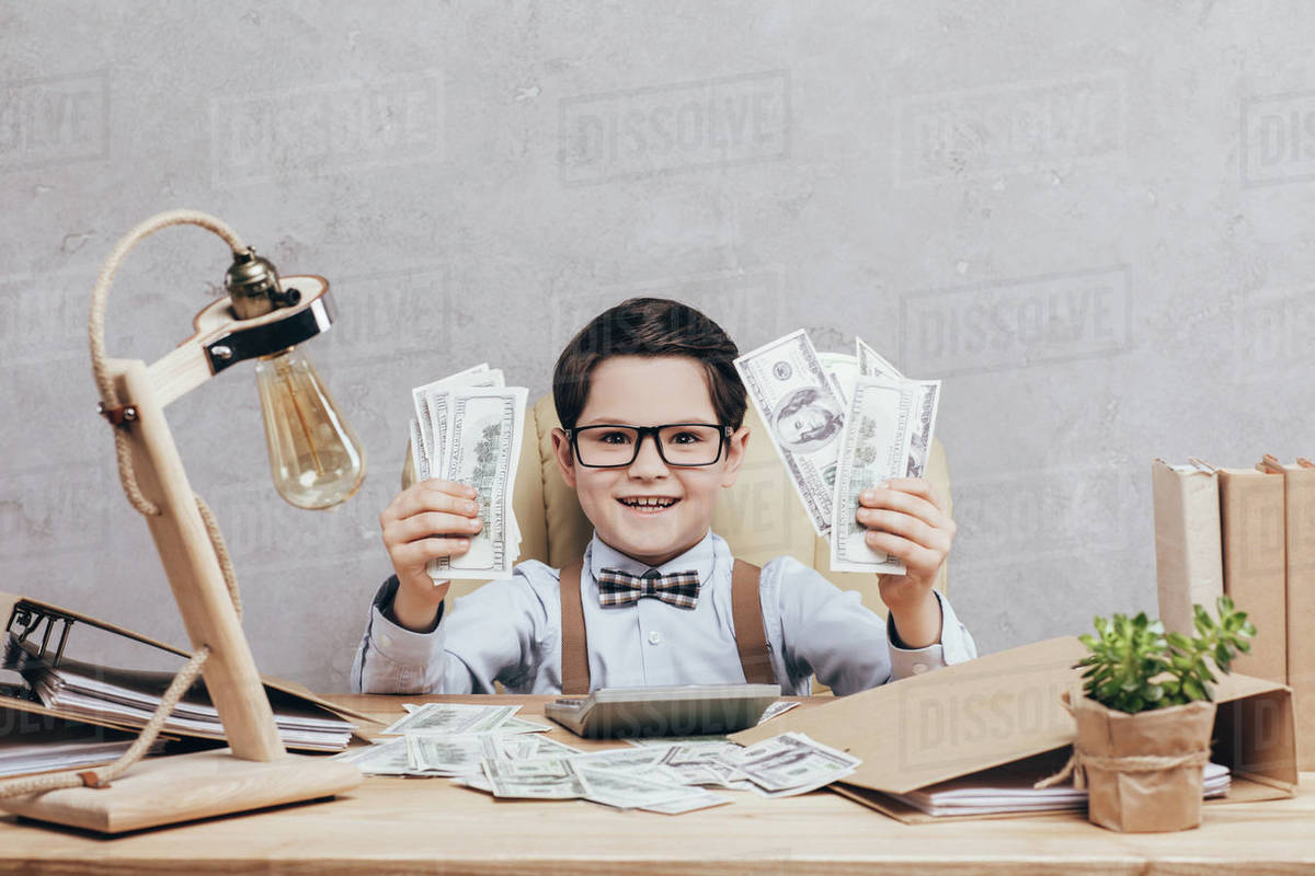 Portrait of excited little boy holding cash in hands and looking at ...