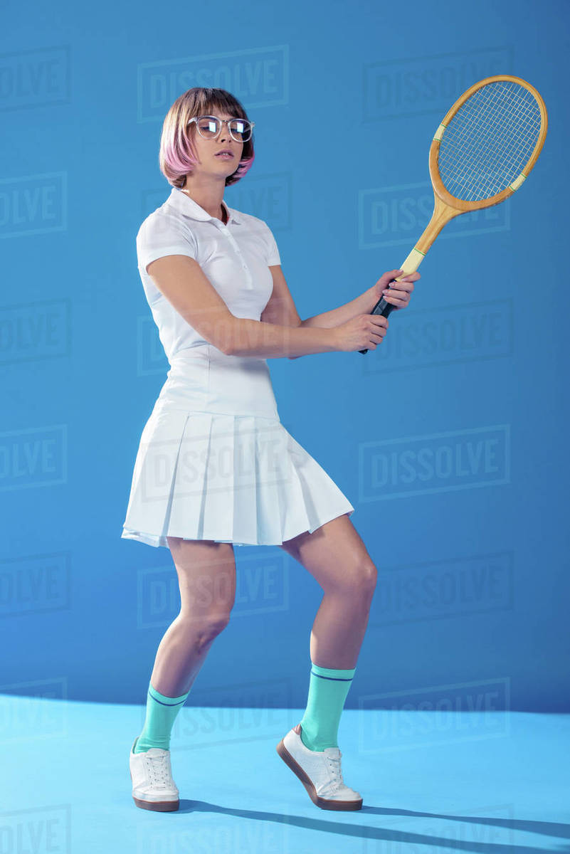 Female tennis player standing in pose with tennis racket on blue ...