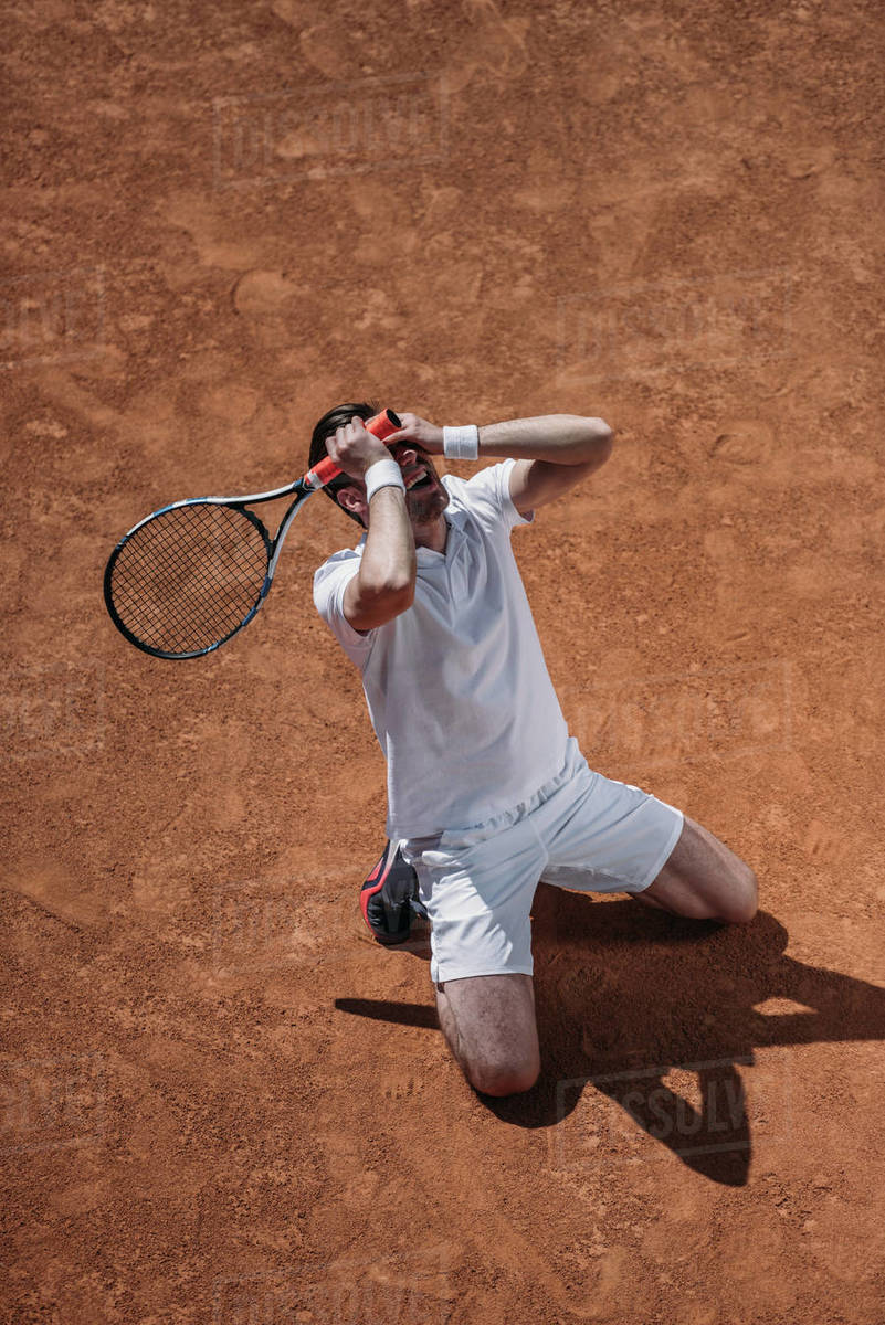 High angle view of man standing on knees and crying after he lose ...