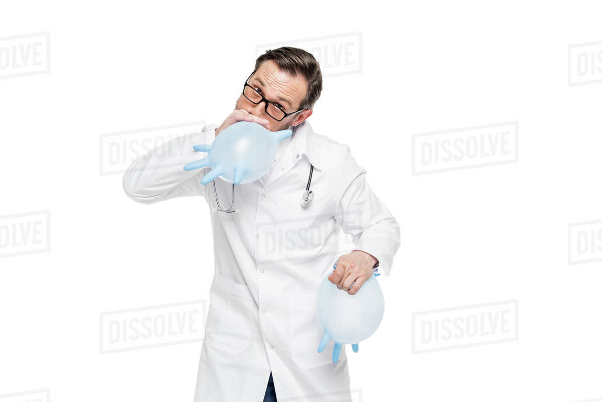 Middle aged doctor in eyeglasses blowing medical gloves isolated on ...