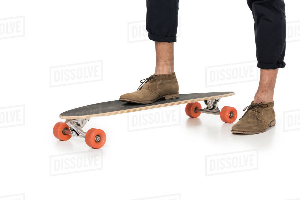 Cropped shot of stylish young man standing on skateboard isolated on ...