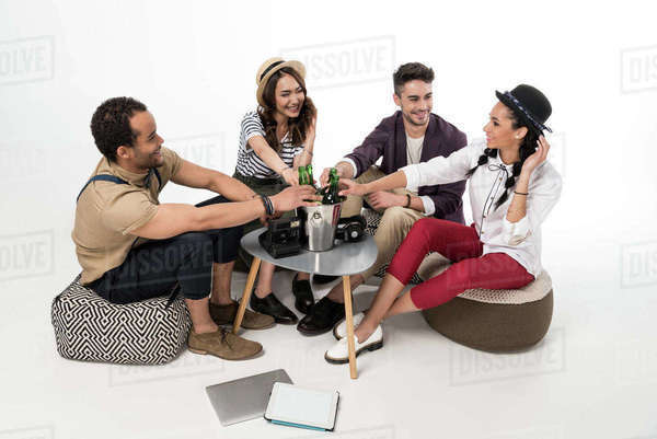 Happy young friends sitting together at table with beer bottles in ...