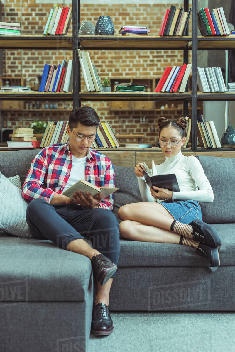 Young asian students in eyeglasses reading books in library - Royalty ...