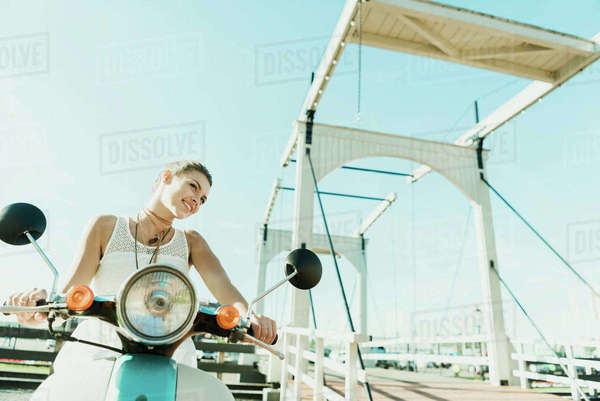 Portrait of happy woman riding retro scooter on street - Royalty-free ...