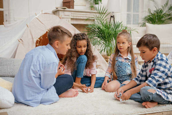 Multicultural children playing domino game together at home - Royalty ...