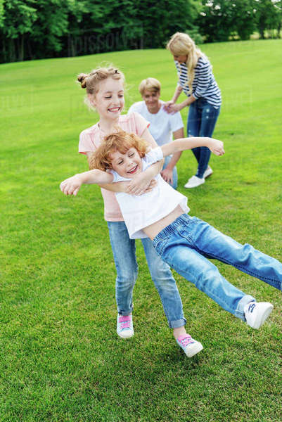 Happy parents looking at cute little children having fun together in ...