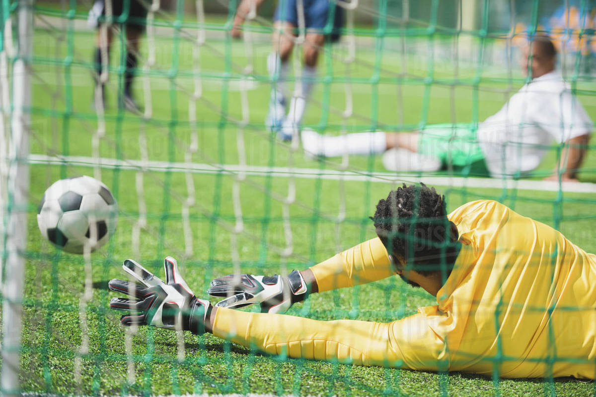 Back view of goalkeeper catching ball during soccer match on pitch ...