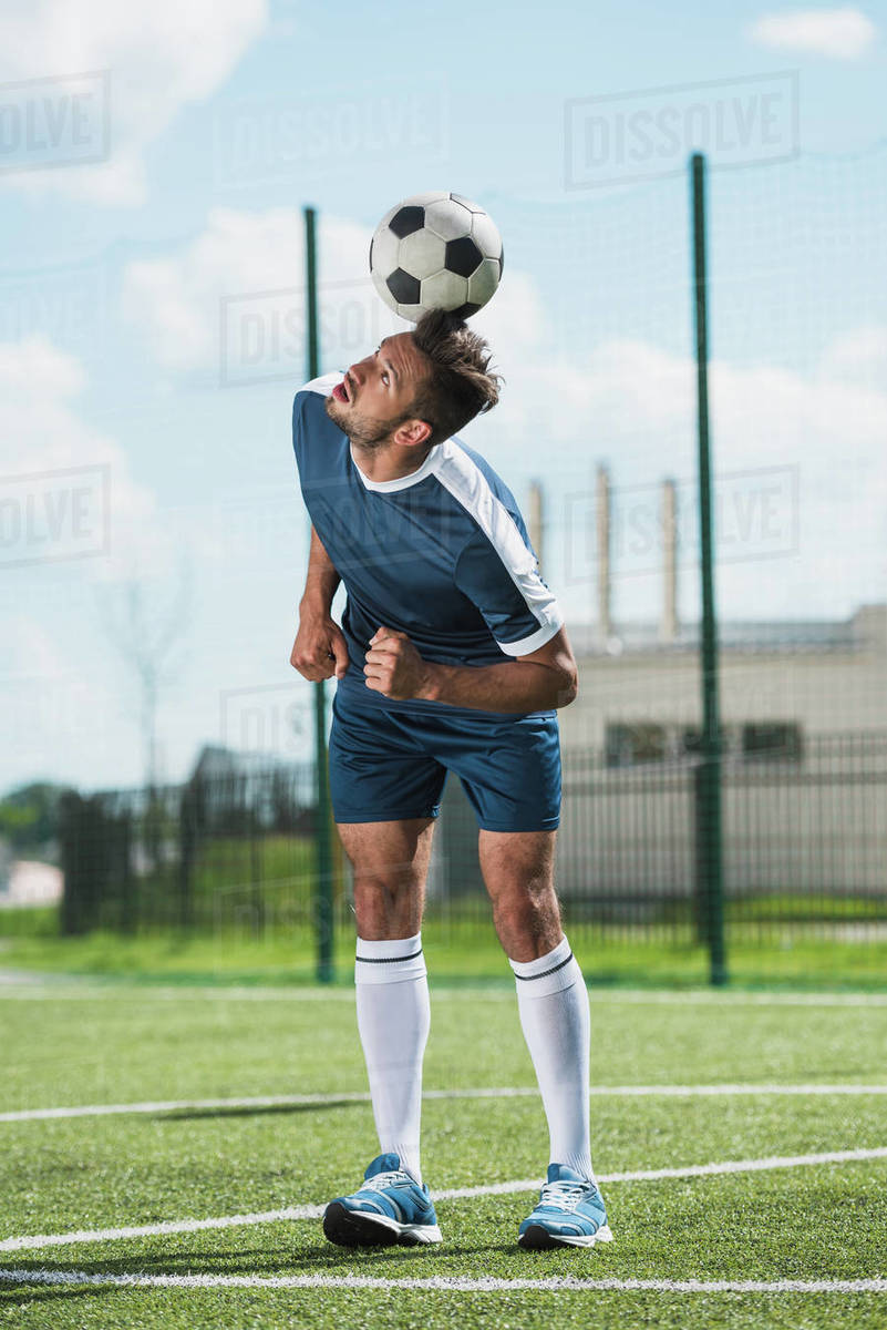 Focused soccer player training with ball on soccer pitch - Royalty-free ...