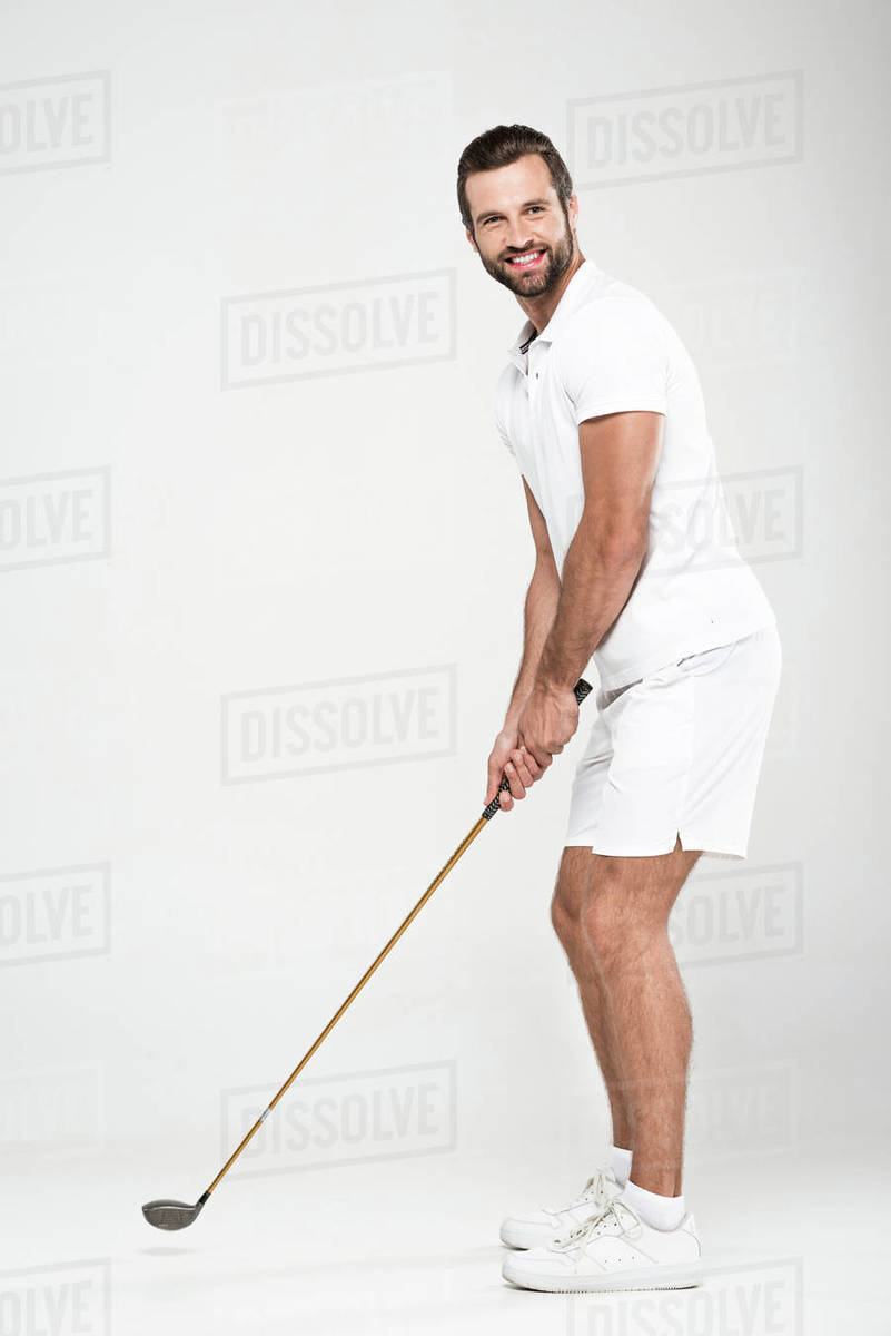 Male golf player in white sportswear with golf club, isolated on grey ...
