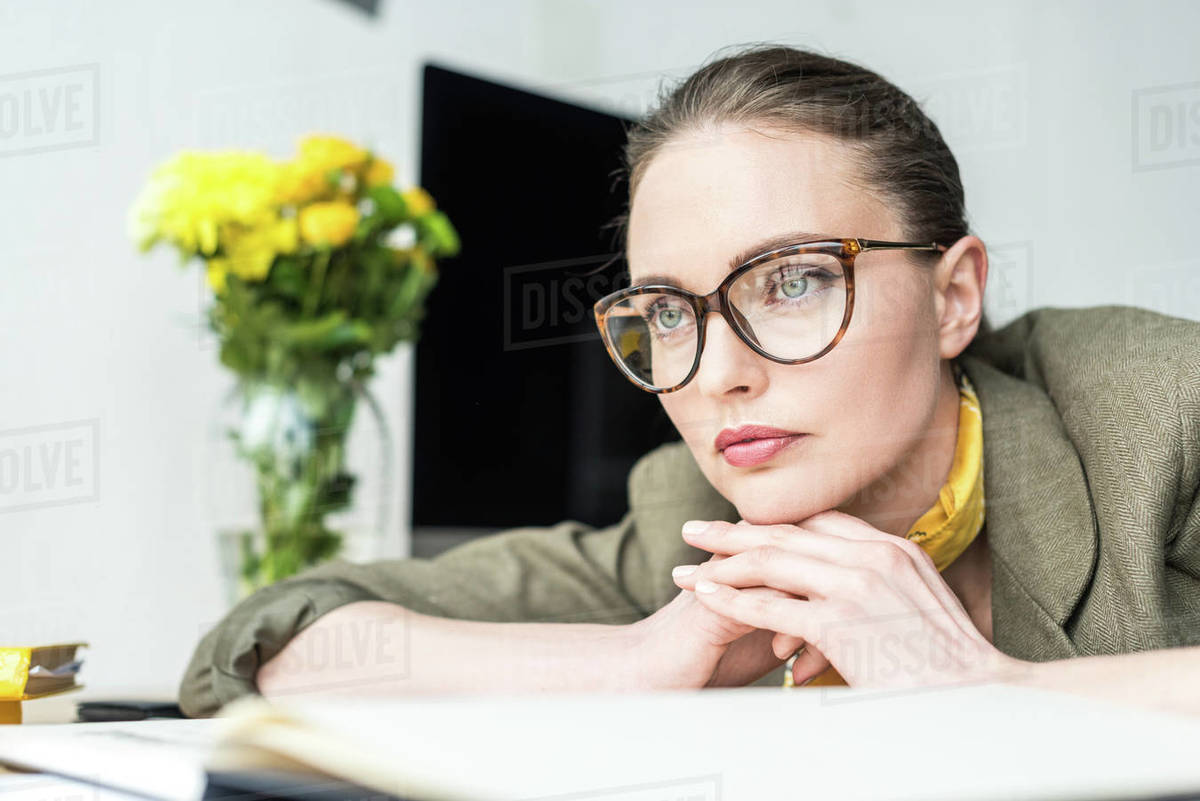 Serious Stylish Businesswoman In Eyeglasses Looking Away In Office