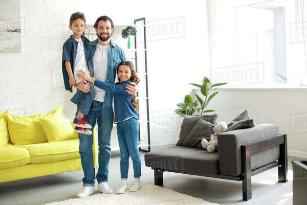 Happy father with two adorable kids smiling at camera at home - Royalty ...